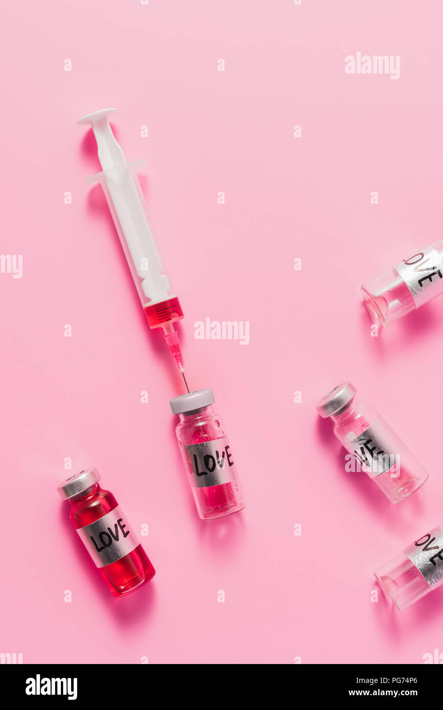 top view of syringe and bottles with love vaccine signs on pink surface ...