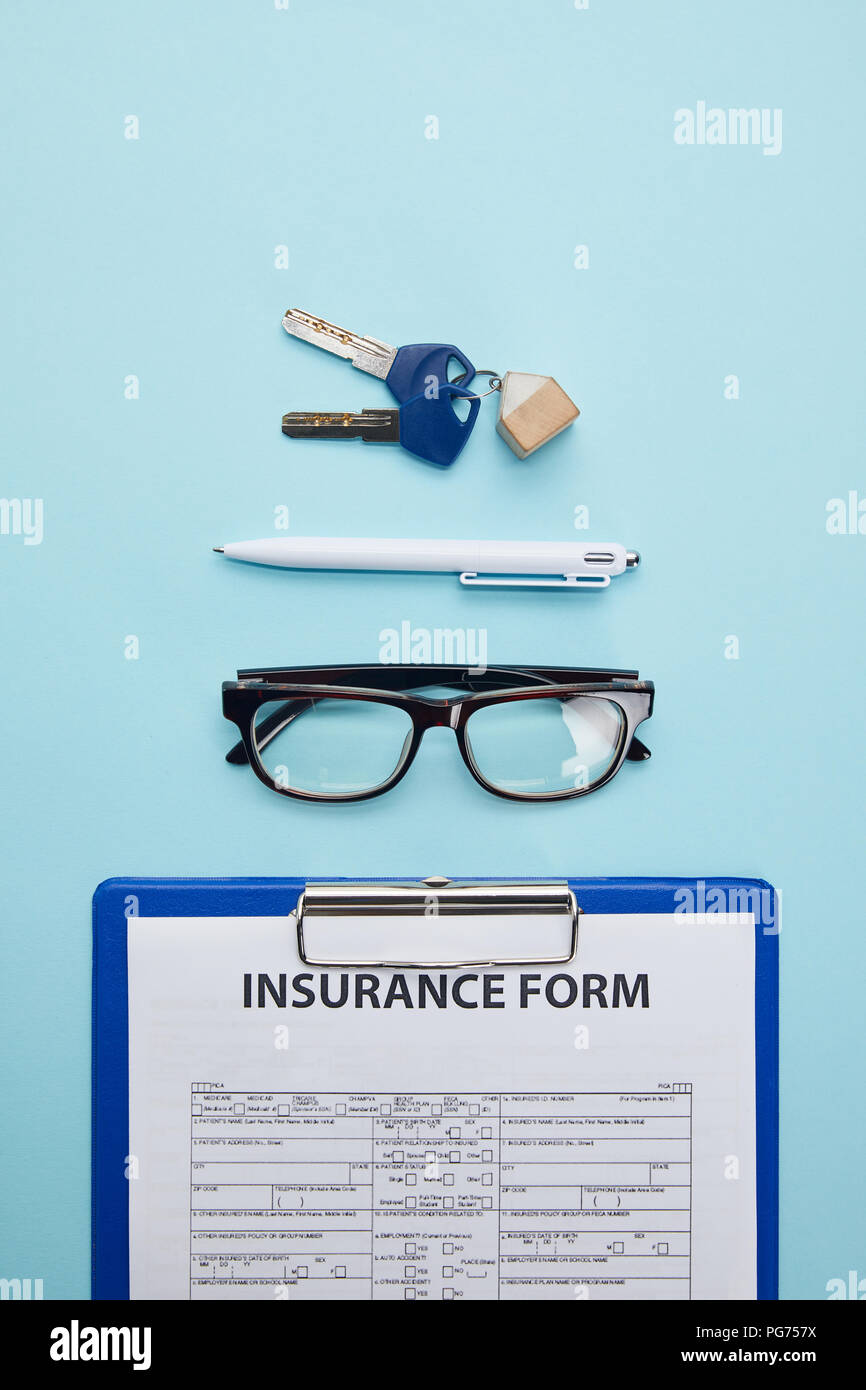 top view of insurance form, eyeglasses, pen and keys isolated on blue ...