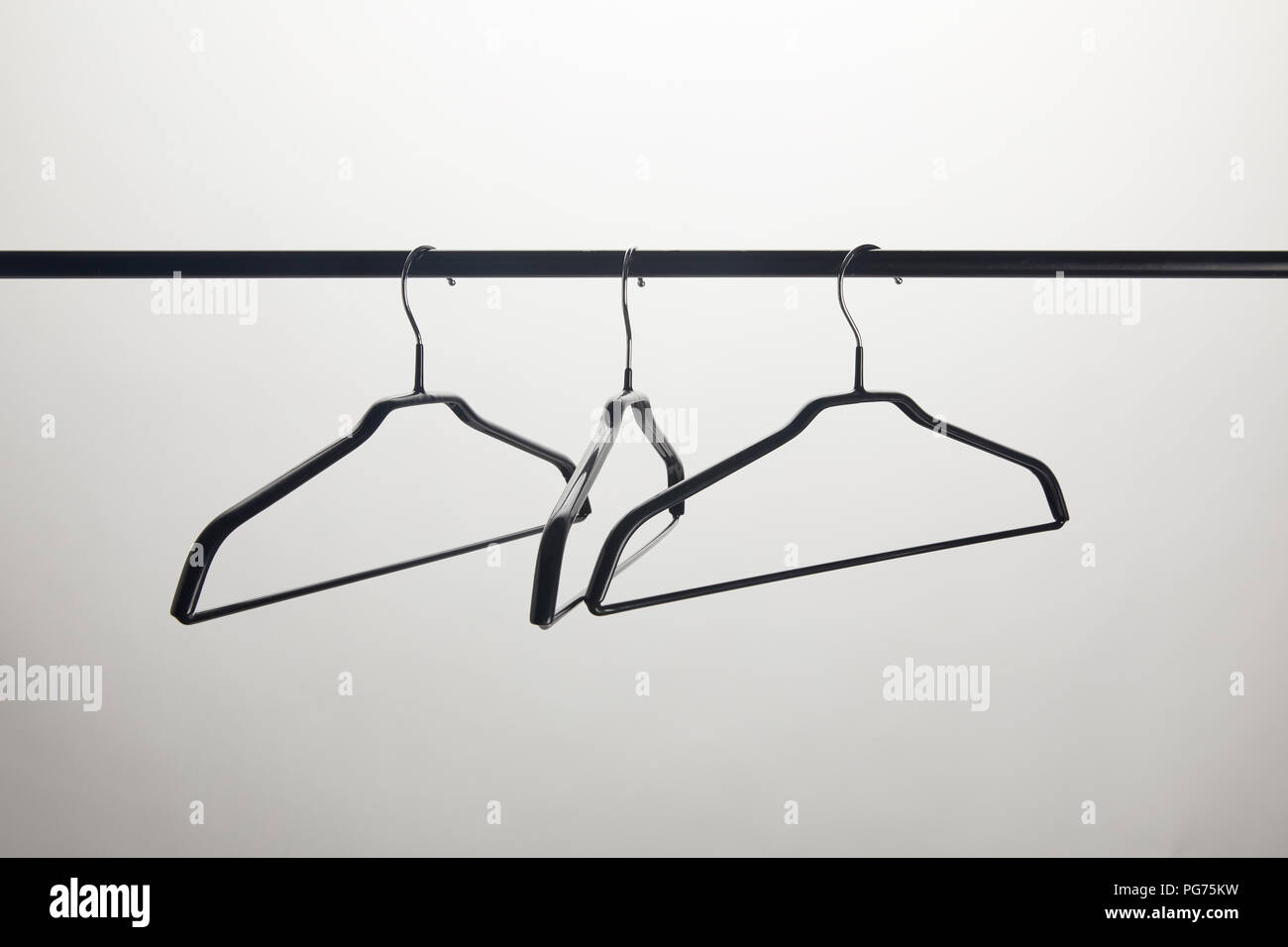 three empty hangers on stand isolated on white Stock Photo - Alamy