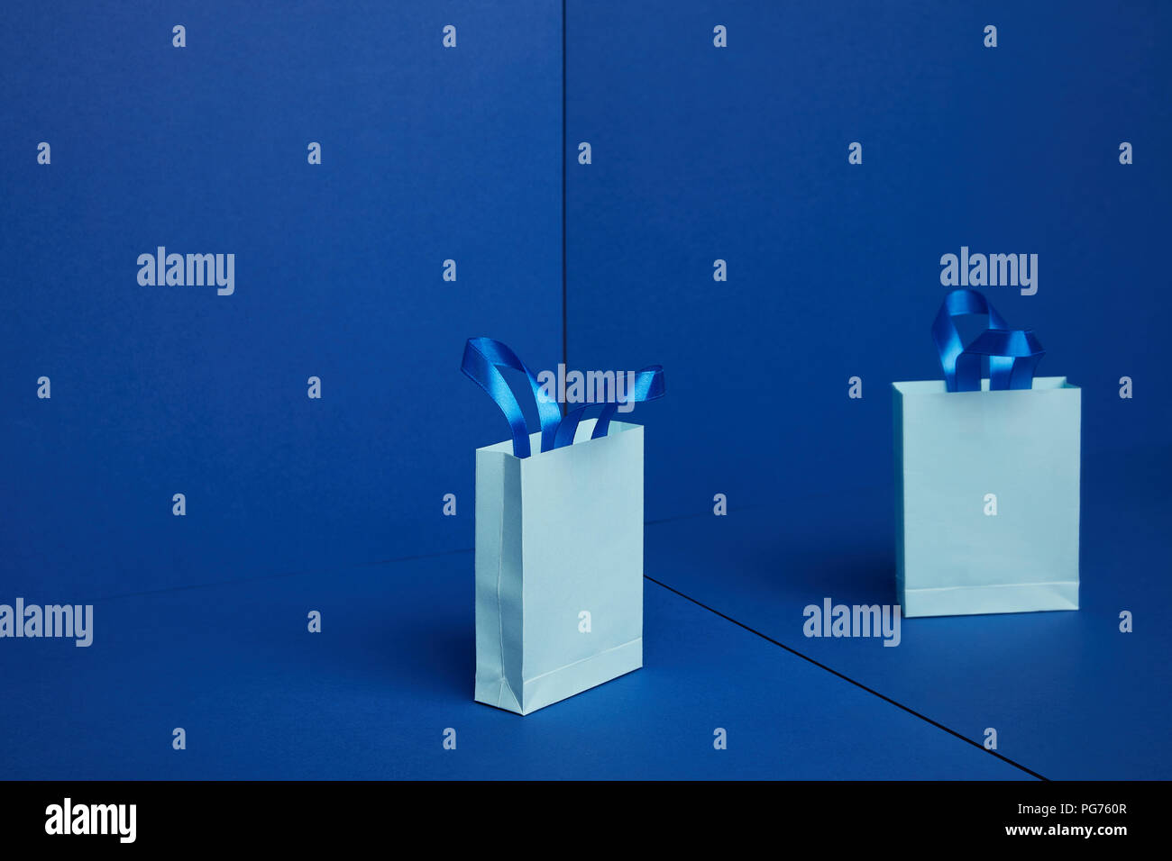 close up view of paper shopping bag with mirror reflection on blue ...