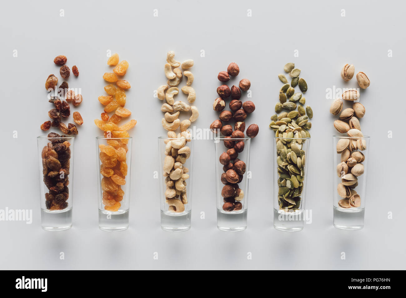 Assorted delicious nuts and raisins in glass cups isolated on white ...