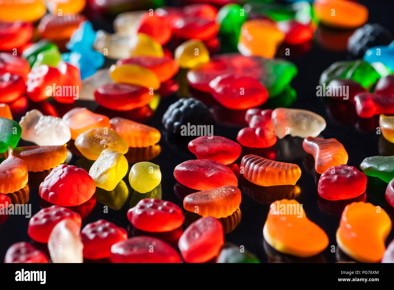 different colored jelly candies on black surface Stock Photo - Alamy
