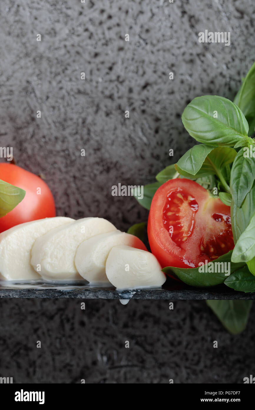 Mozzarella with basil and tomatoes on a background of old grey wall ...
