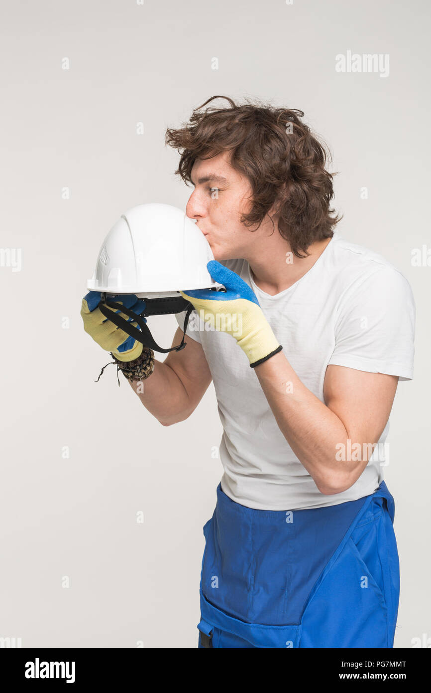Portrait of funny caucasian male builder kissing helmet on white ...