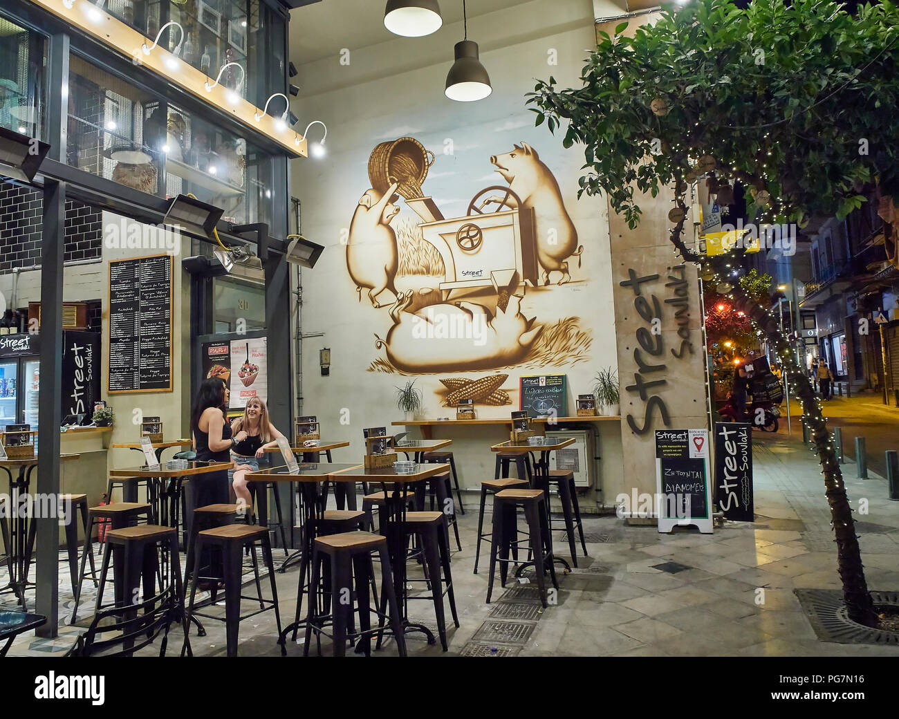 Two girls in a terrace of a Greek bar at Plaka neighborhood of Athens ...
