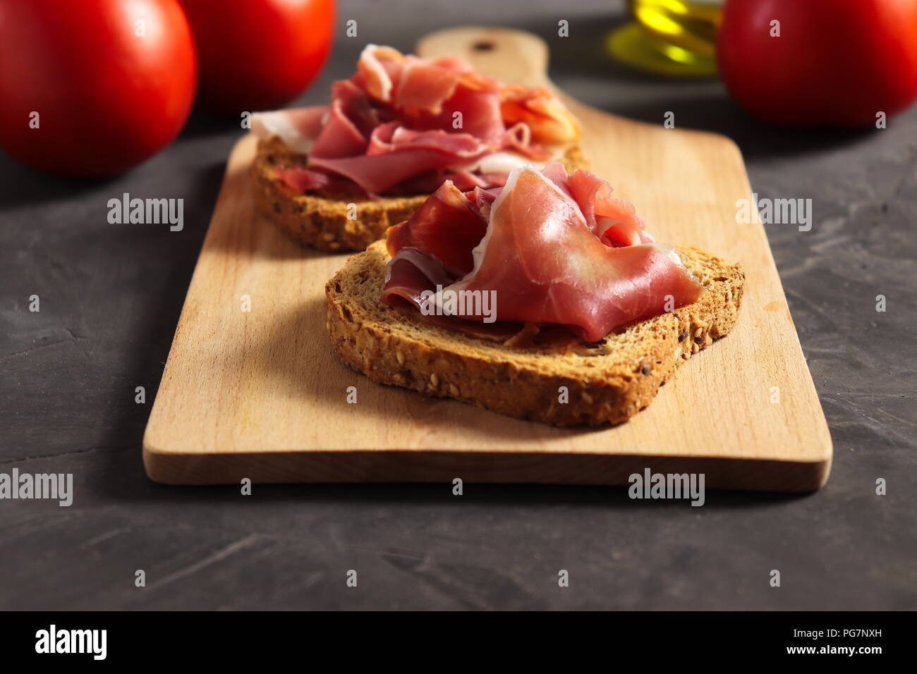Spanish ham (jamon) on a piece of toasted whole grain bread, tomatoes ...