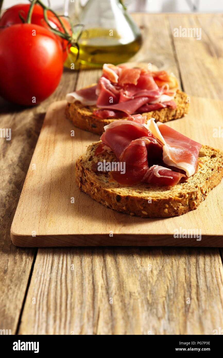 Spanish ham (jamon) on a piece of toasted whole grain bread, tomatoes ...