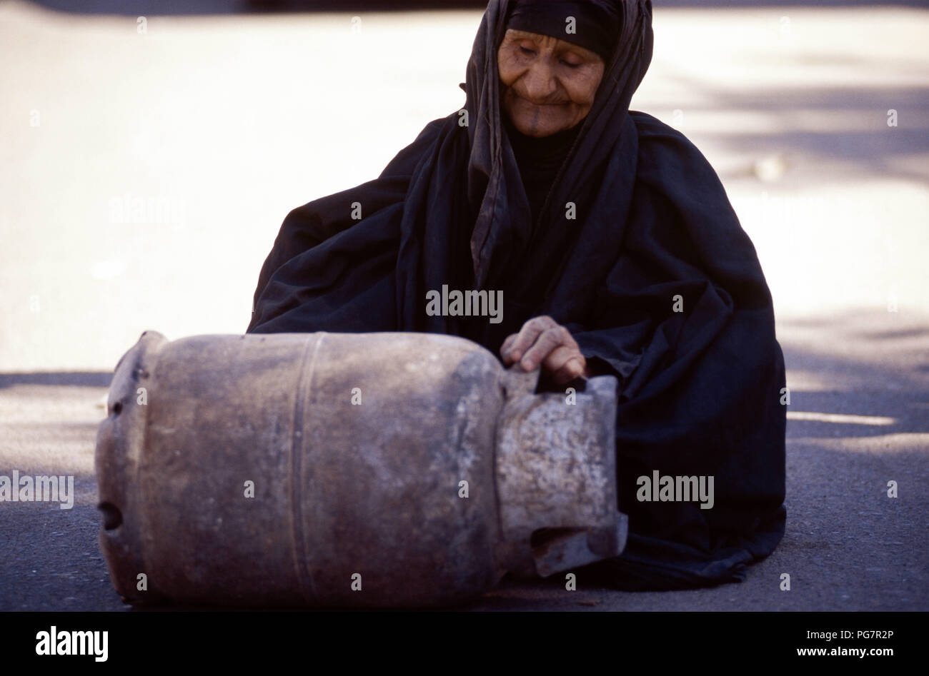Baghdad, Iraq - October 1995 - An elderly Iraqi woman rolls a butane ...