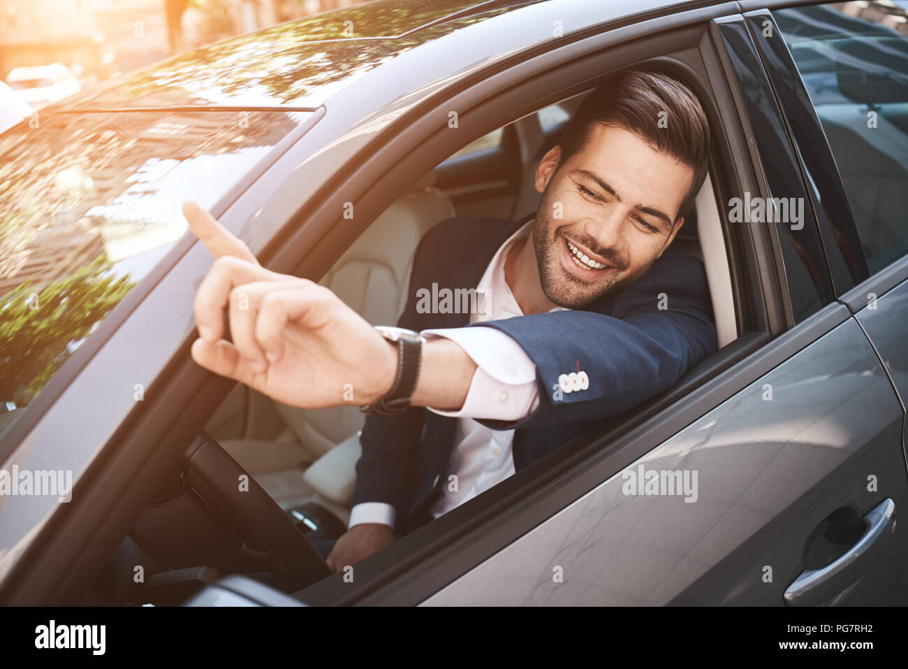 Portrait of businessman driving in car and smiling on his morning ...