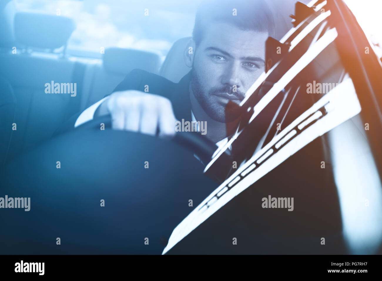 Businessman in car. Rear view of young handsome man looking on the road ...