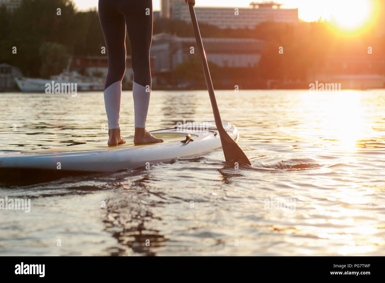 SUP confident woman swimsuit standing with a paddle on the surfboard ...