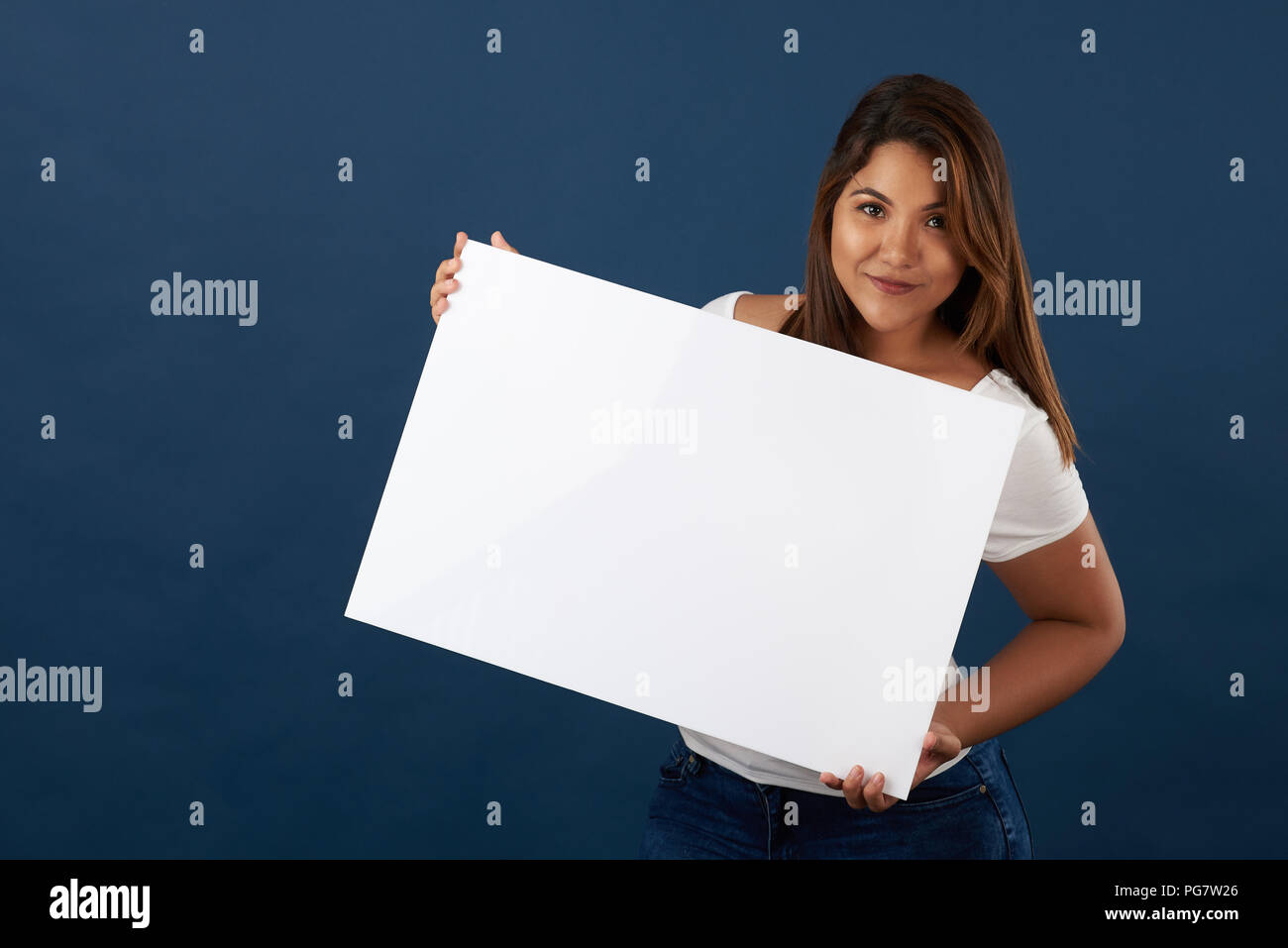 Teenager girl show blank empty sign on blue studio background isolated ...