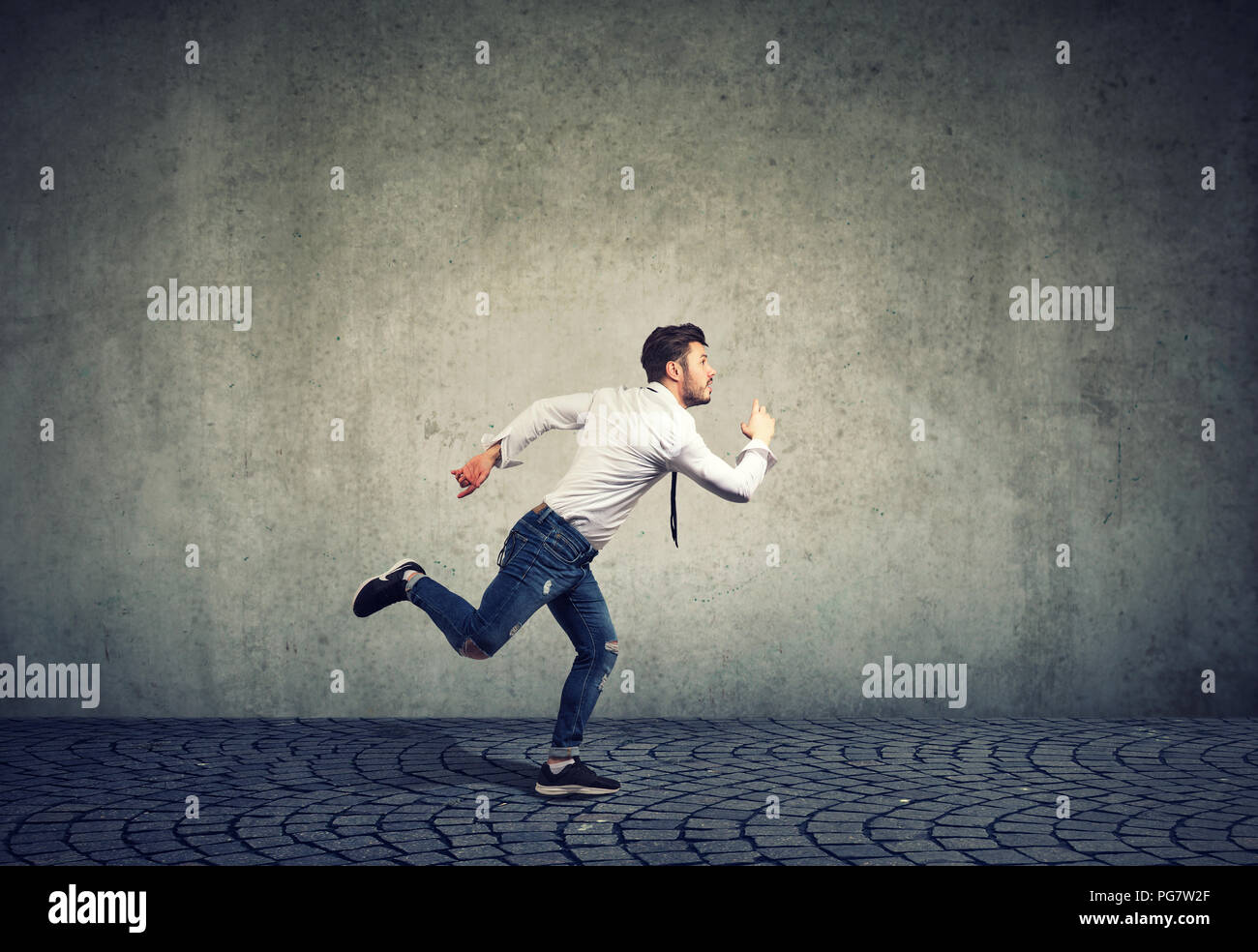 Busy running young business man on gray wall background Stock Photo - Alamy
