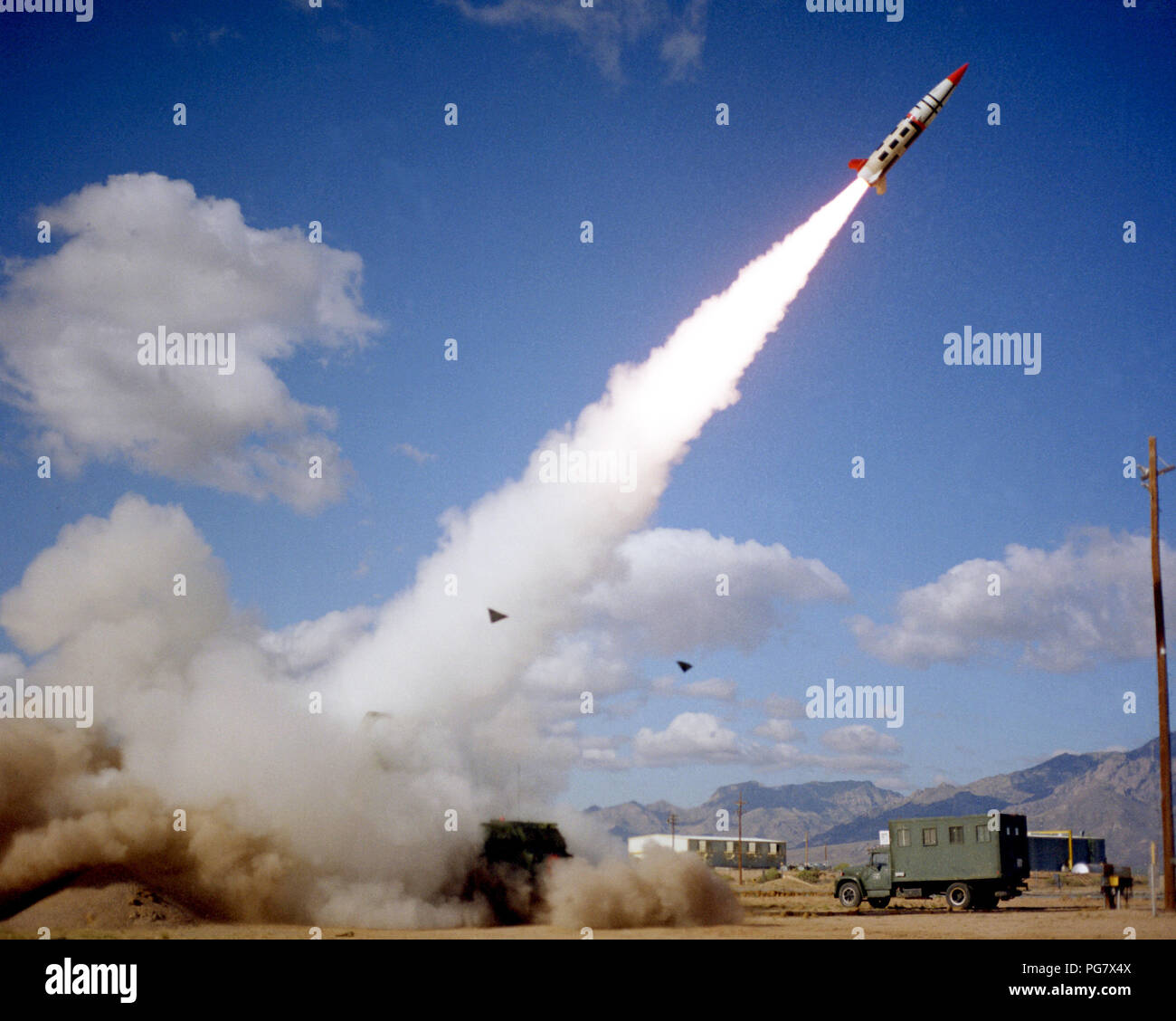 Smoke and dust surround a Multiple-Launch Rocket System (MLRS) launcher ...