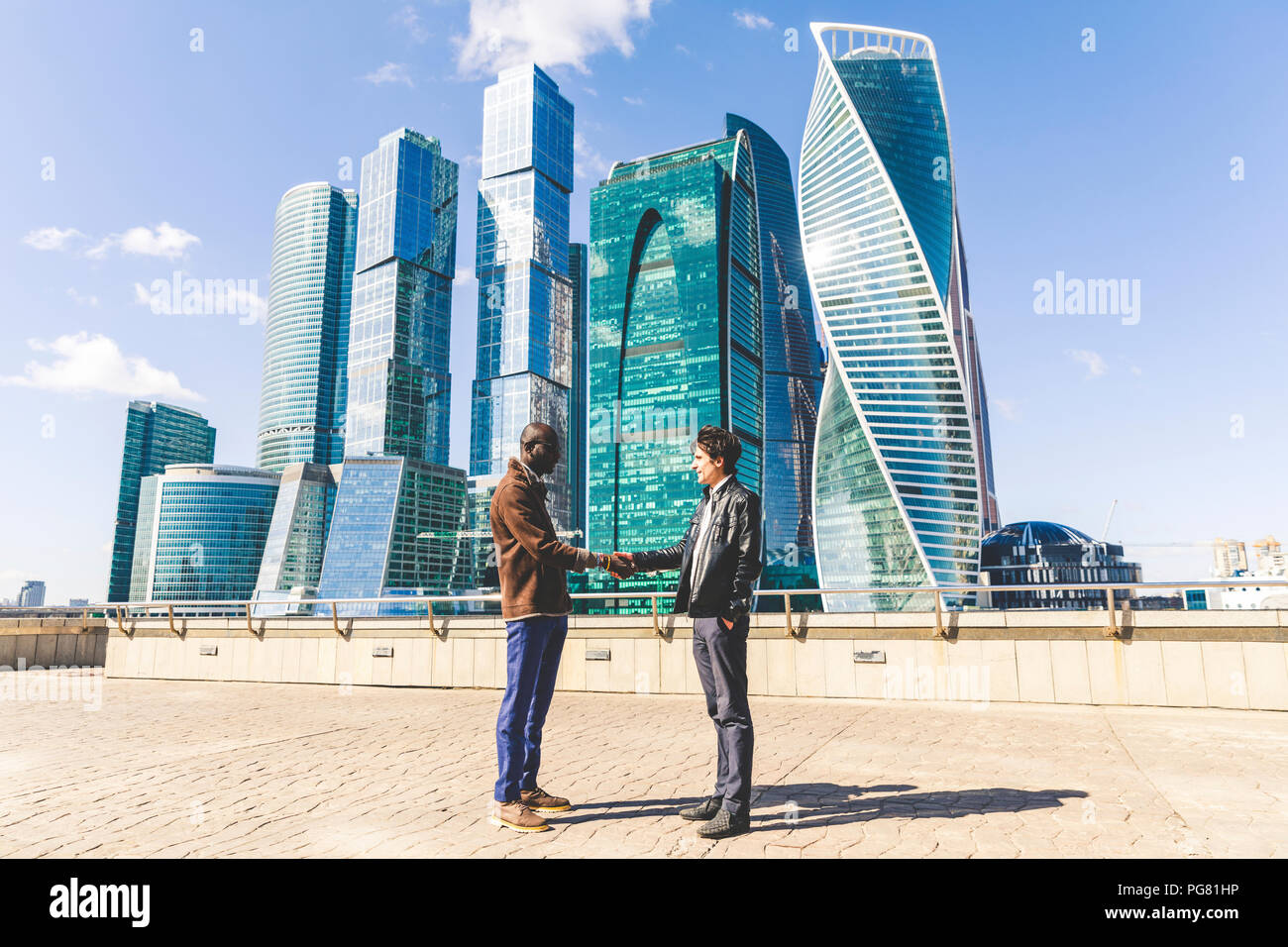 Russia, Moscow, two businessmen shaking hands in front of modern office ...