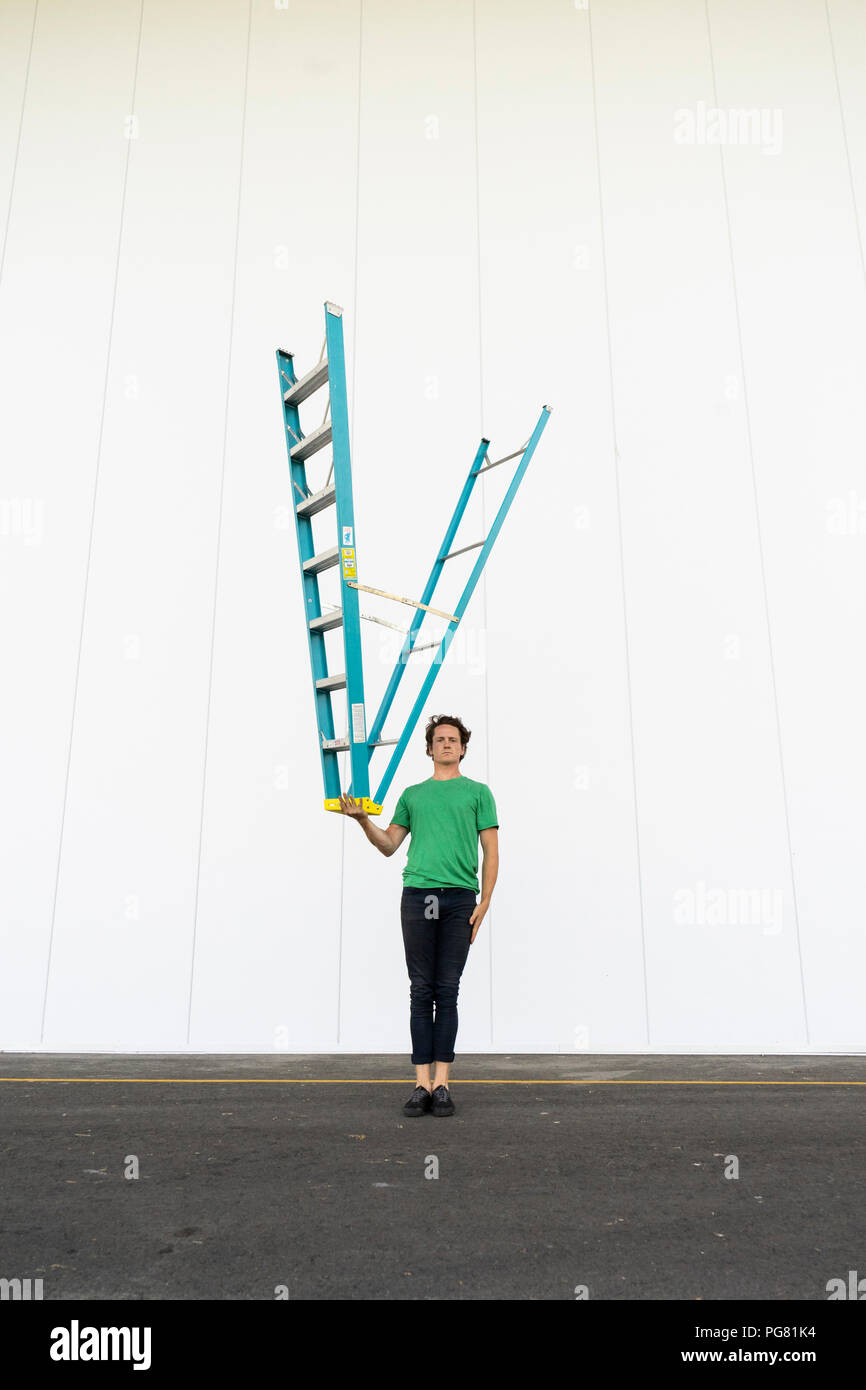 Acrobat balancing ladder upside down in his hand Stock Photo - Alamy
