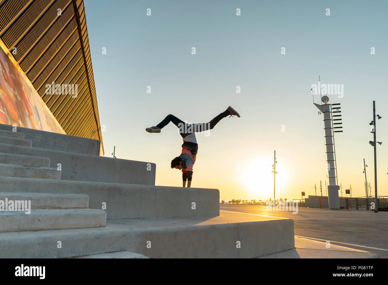 Acrobat doing handstand on stairs at sunrise Stock Photo - Alamy