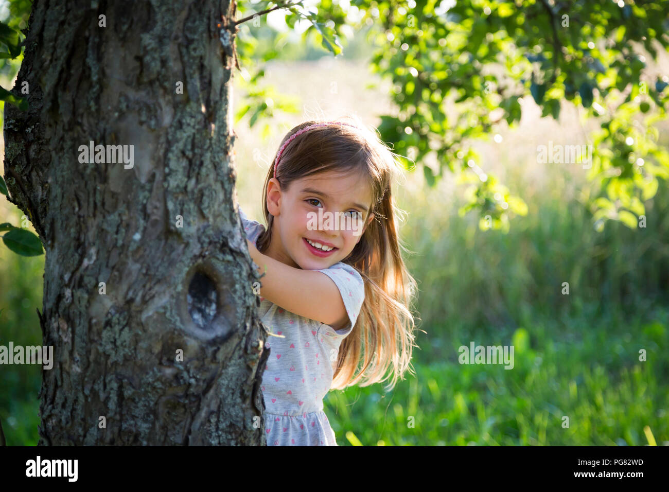 Children hiding in behind tree hi-res stock photography and images - Alamy
