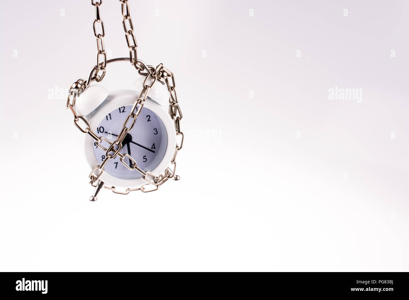 White color alarm clock in chain on a white background Stock Photo - Alamy
