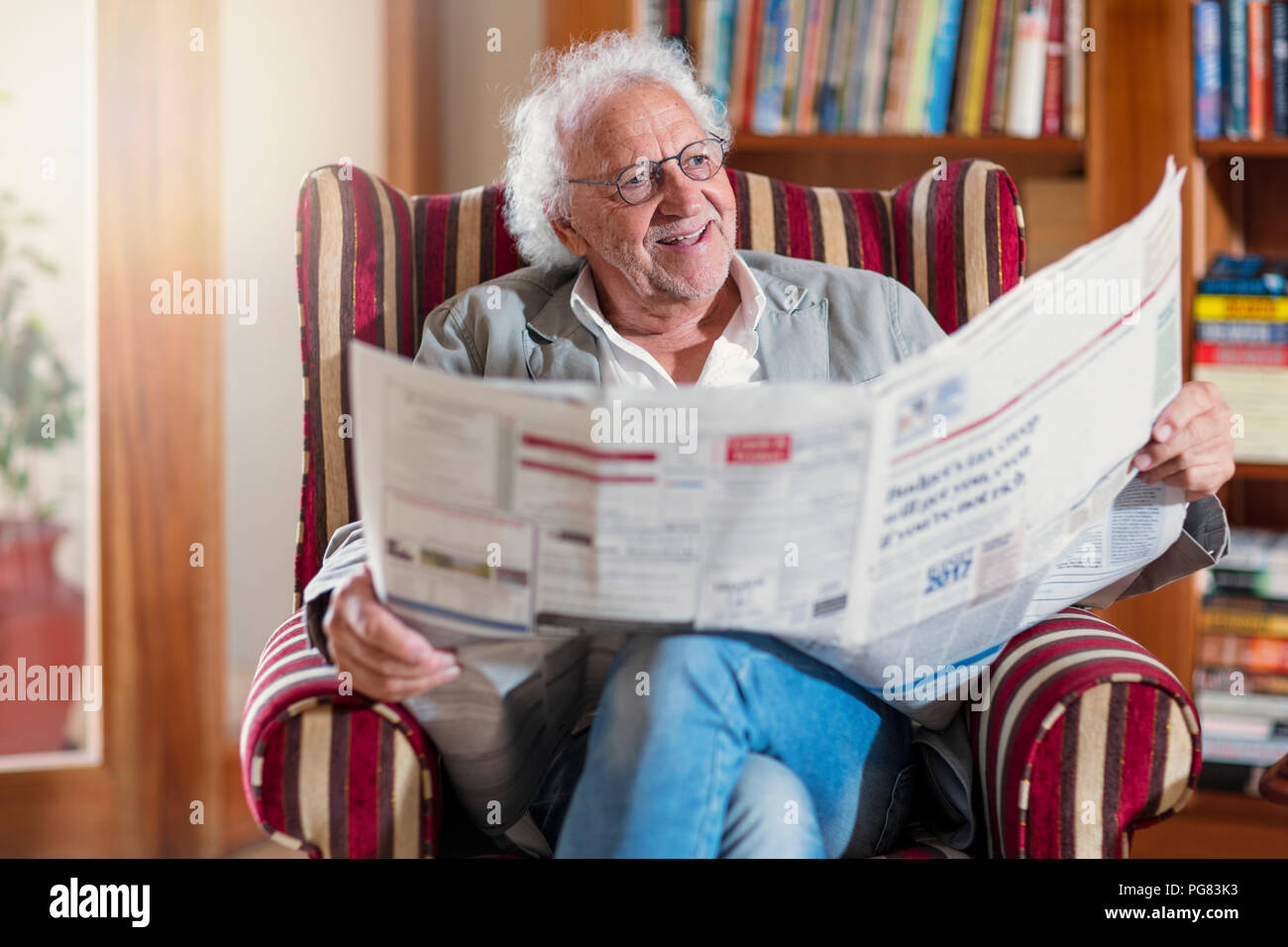 Senior man sitting in library, reading newpaper Stock Photo - Alamy