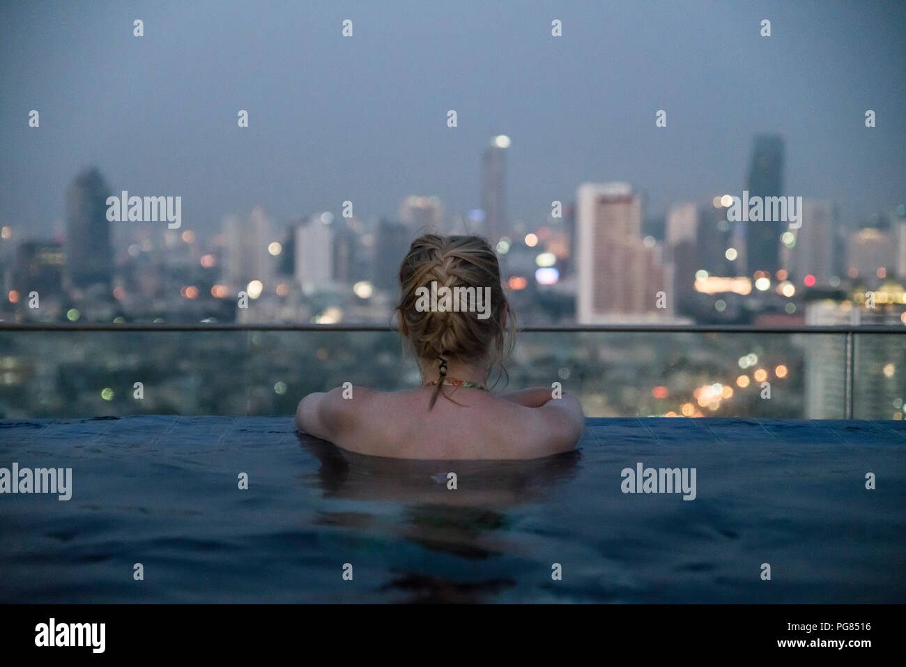 Thailand, Bangkok, back view of woman bathing in Infinity Pool looking ...