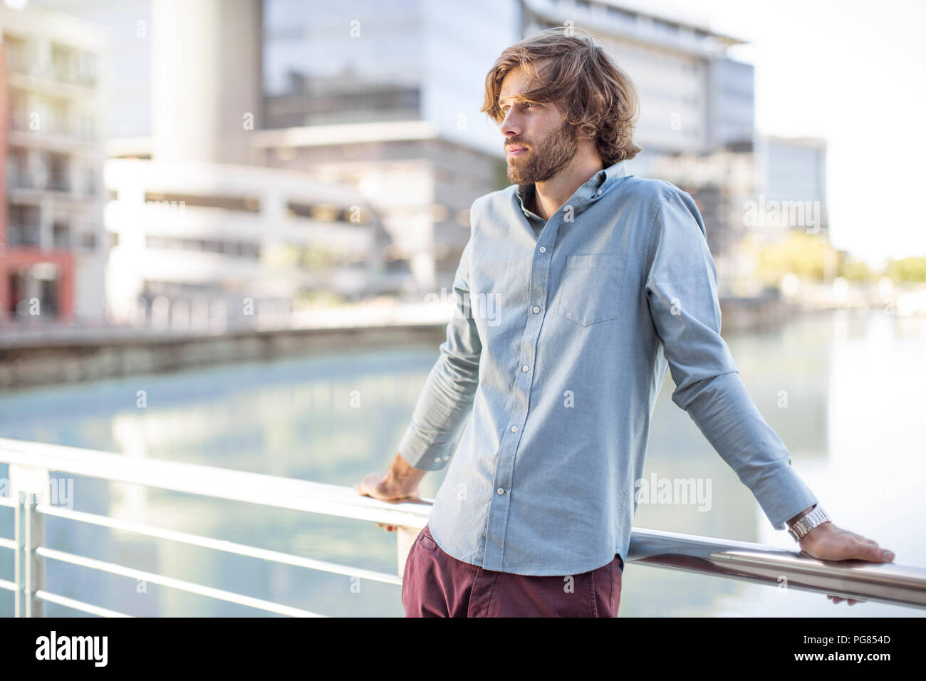Young man taking a break, leaning on railing Stock Photo - Alamy