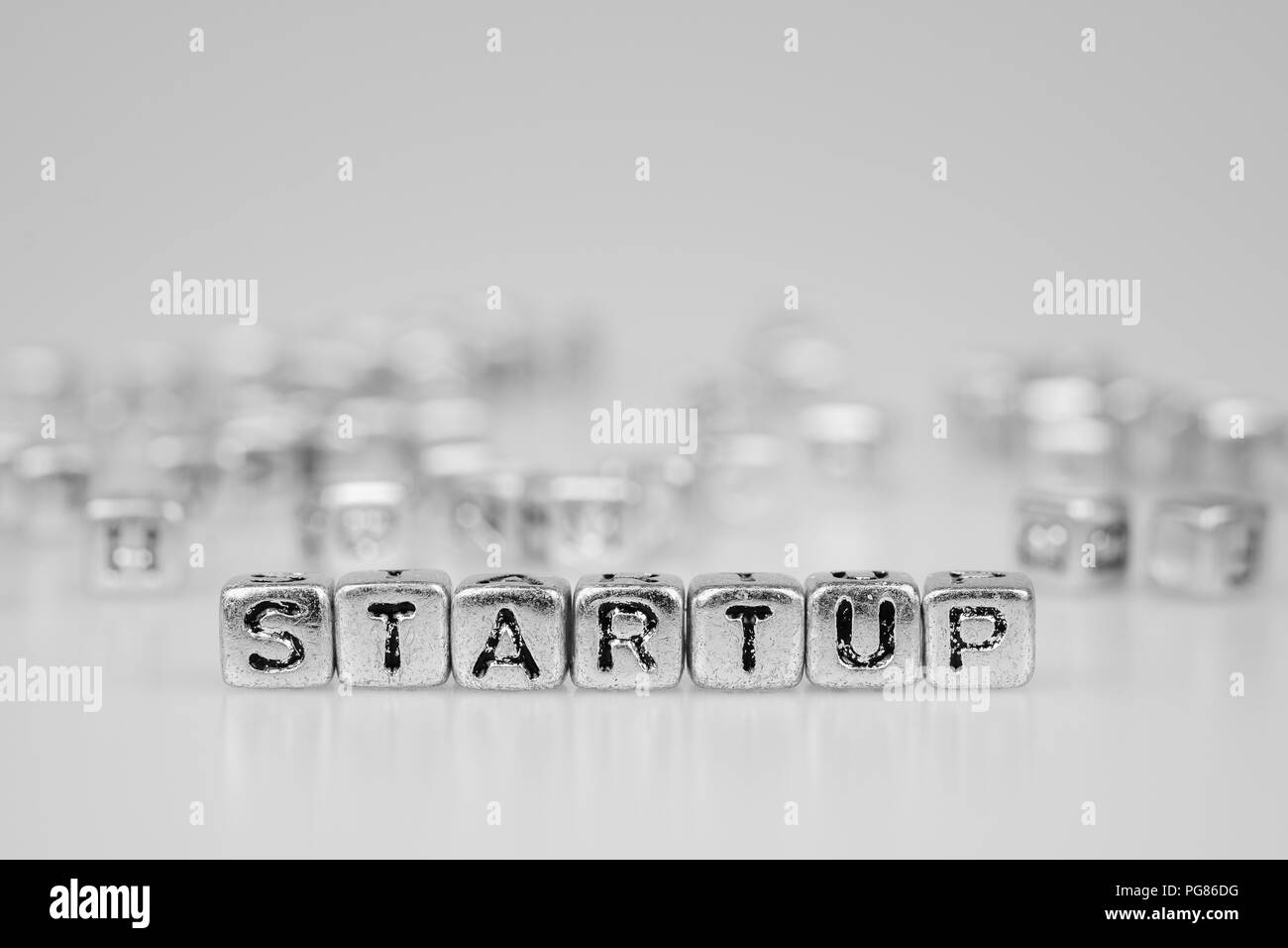 Startup word written on silver cube with black and white bokeh cube ...