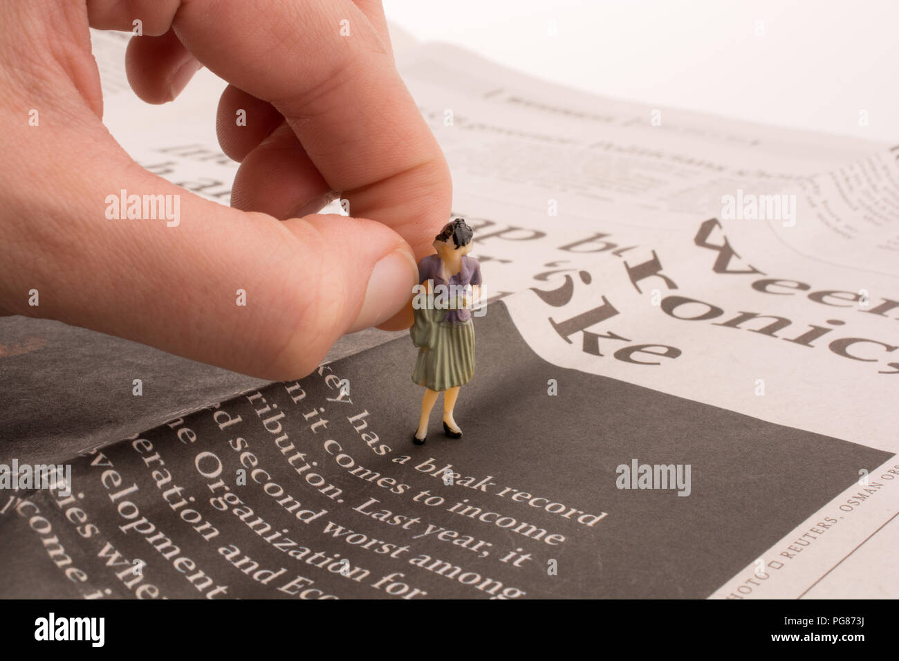 Hand holding a human figure on a newspaper Stock Photo - Alamy