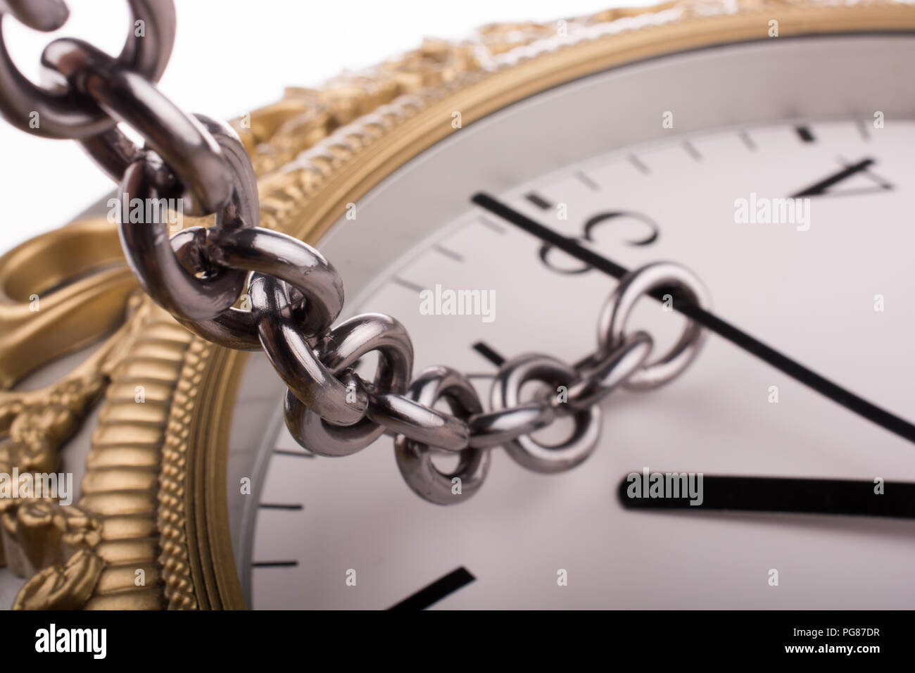 chain tied to minute hand of a clock and pulled on a white background ...