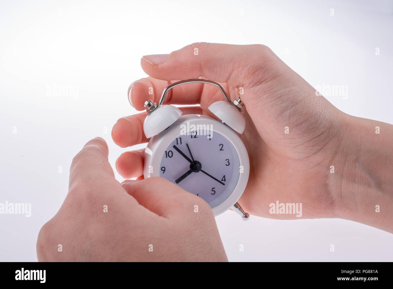 Alarm clock in hand on a white background Stock Photo - Alamy