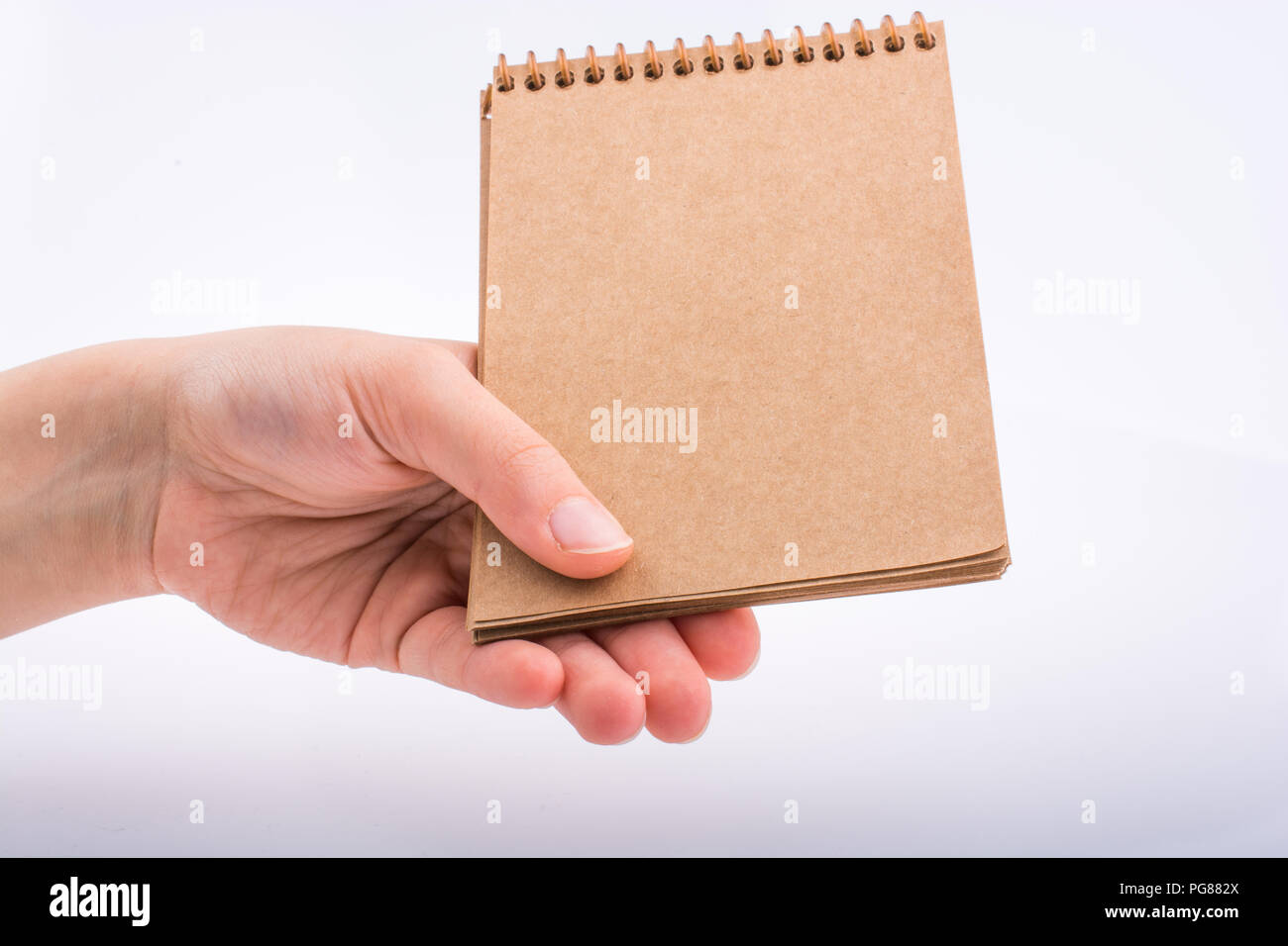Hand holding a brown spiral notebook on a white background Stock Photo ...