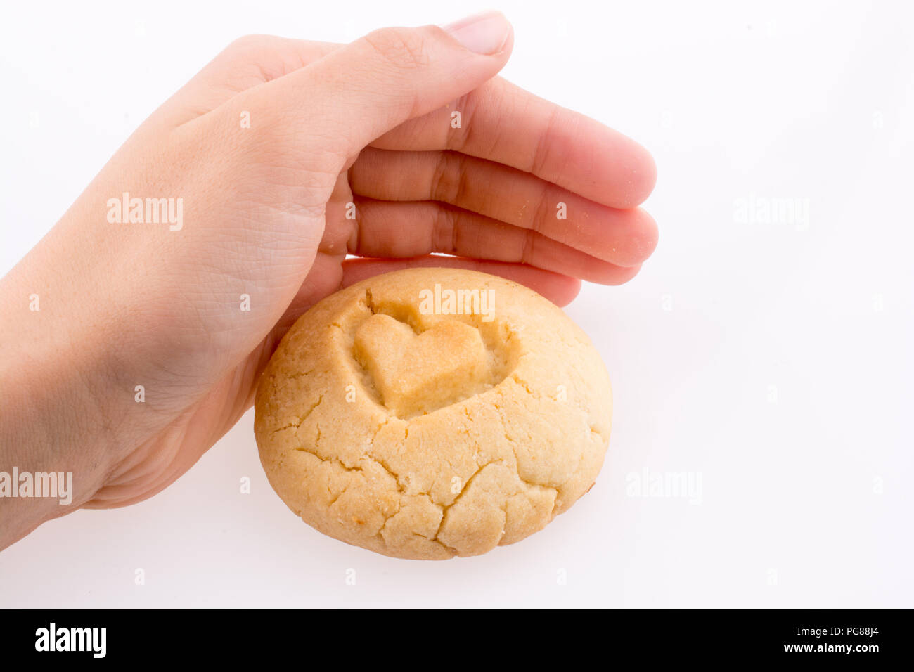 Hand holding a Light brown cookie with a pattern on a white background ...