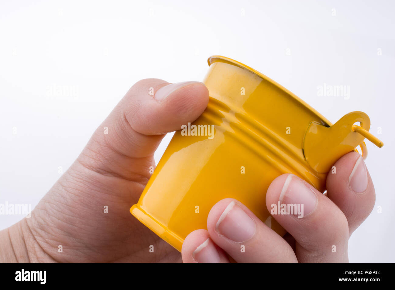 Hand holding a yellow bucket on a white background Stock Photo - Alamy