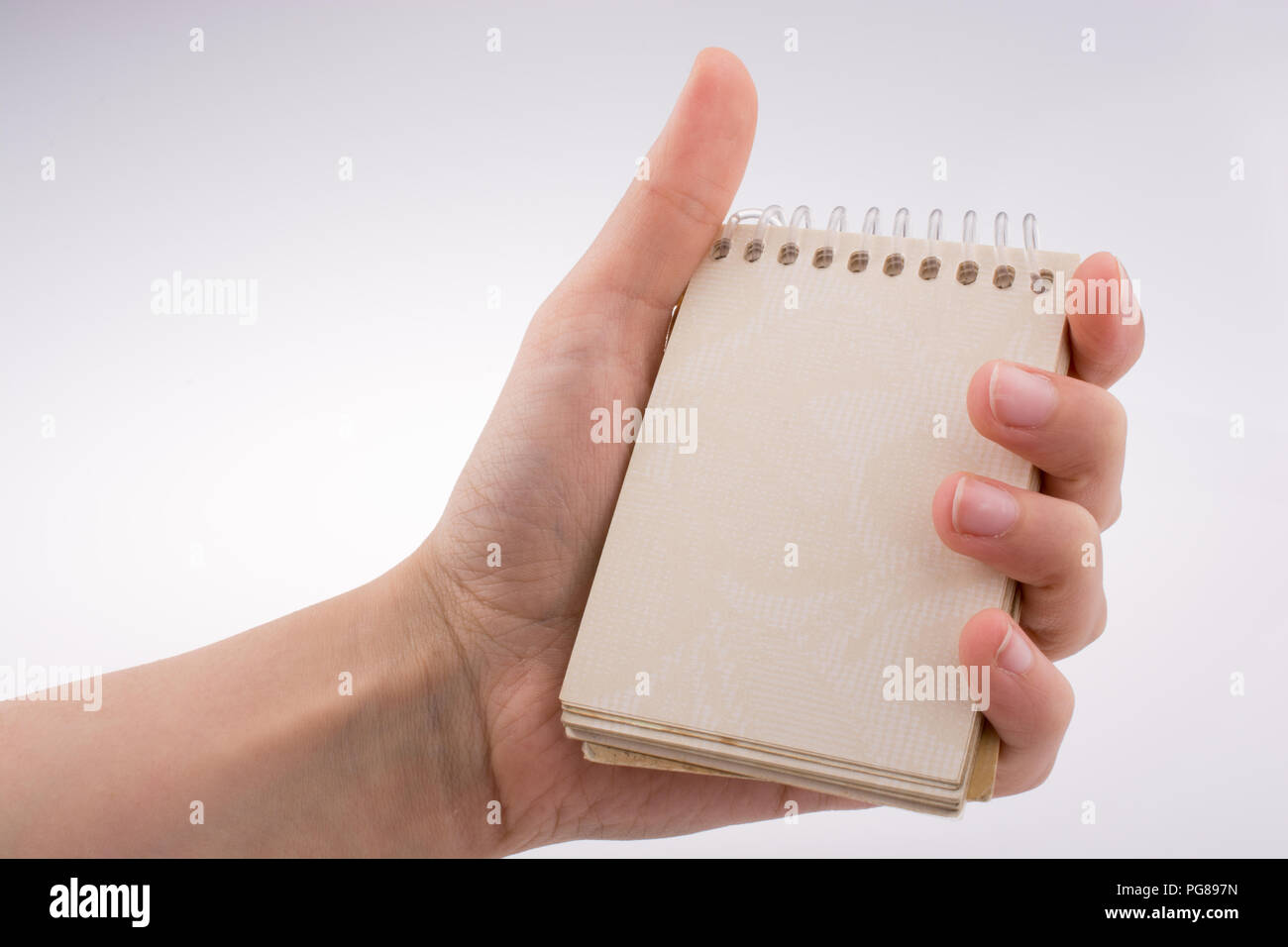 Hand holding a spiral notebook on a white background Stock Photo - Alamy
