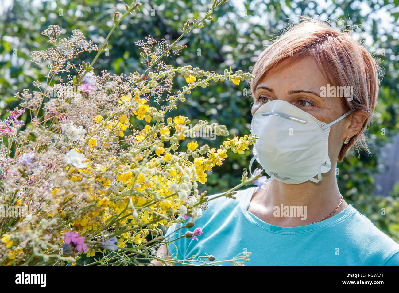 Woman in protective mask holding bouquet of wildflowers and trying to ...
