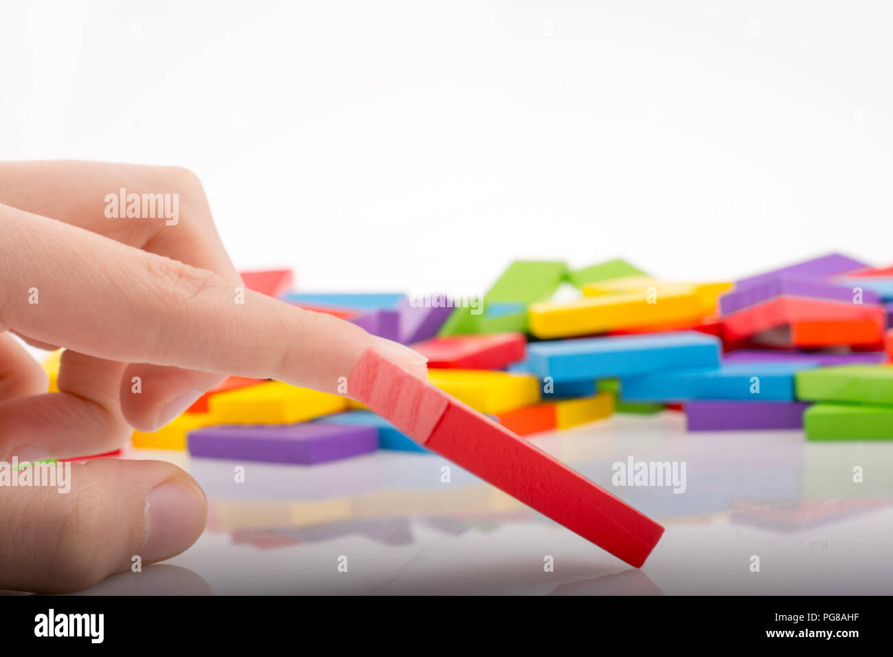 Hand playing with colored domino on white background Stock Photo - Alamy