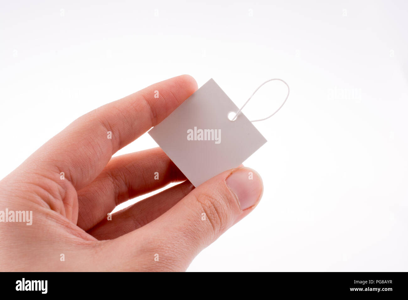 Hand holding a white tag with string Stock Photo - Alamy