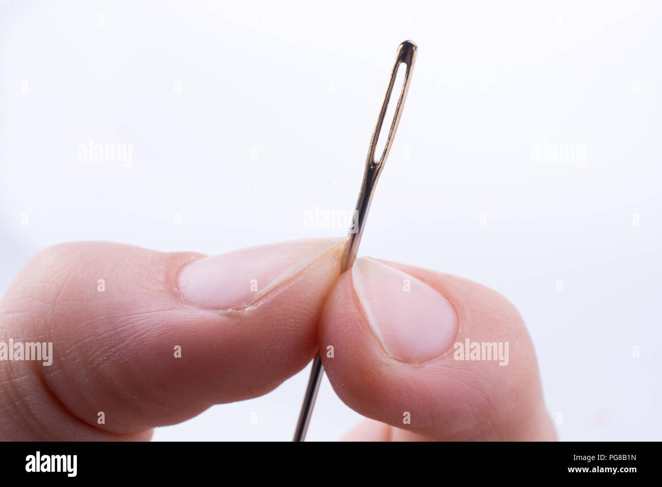 Hand holding a needle on a white background Stock Photo - Alamy