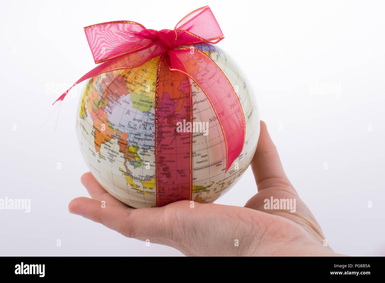 Globe tied with red ribbon on a white background Stock Photo - Alamy