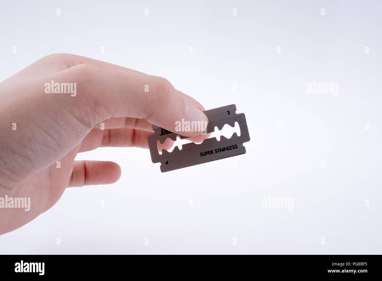 Hand holding a razor blade on a white background Stock Photo - Alamy