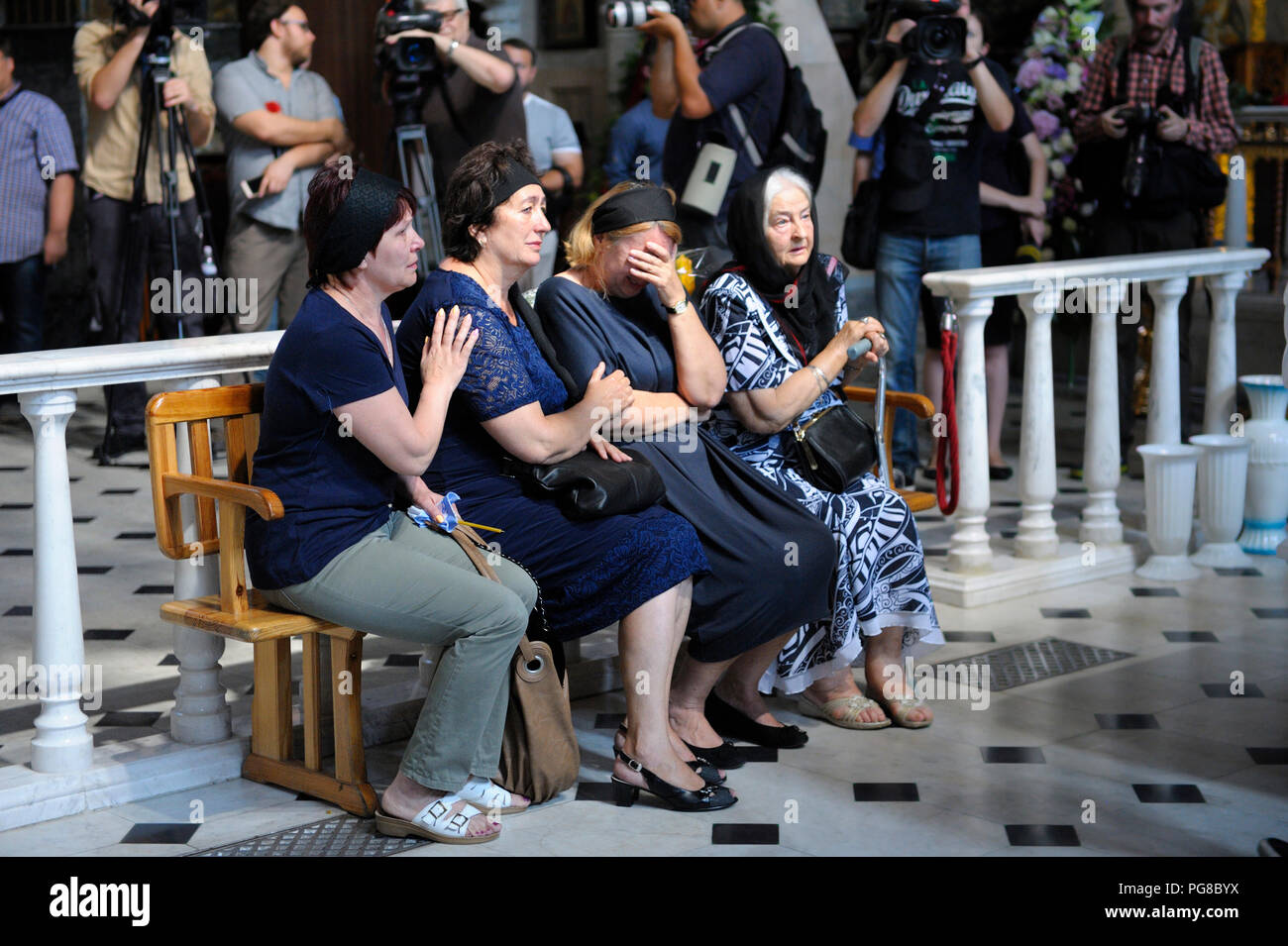 Burial service in a church: relatives sit on a bench in front of a ...