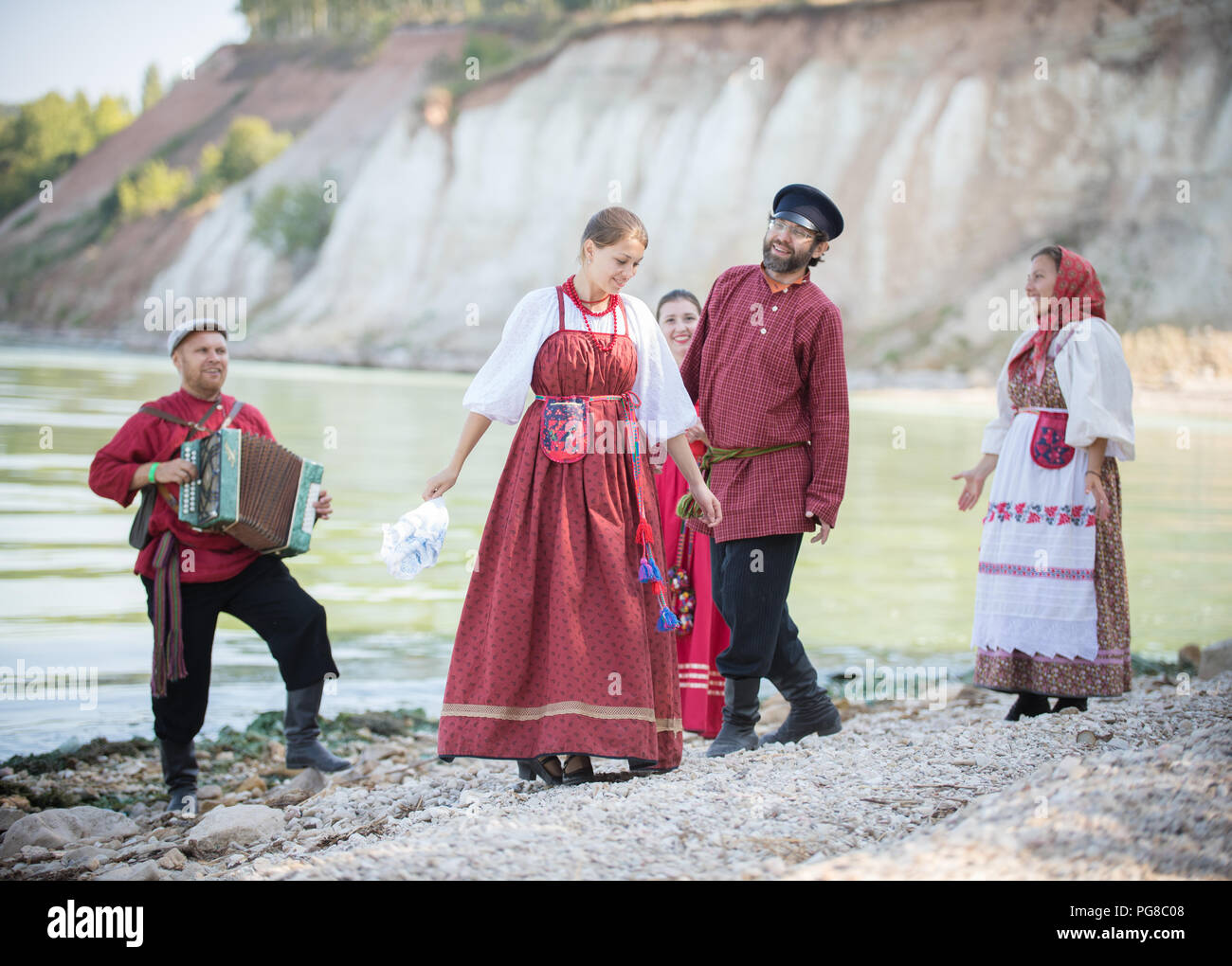 A group of friends in national Russian costumes dancing against a ...