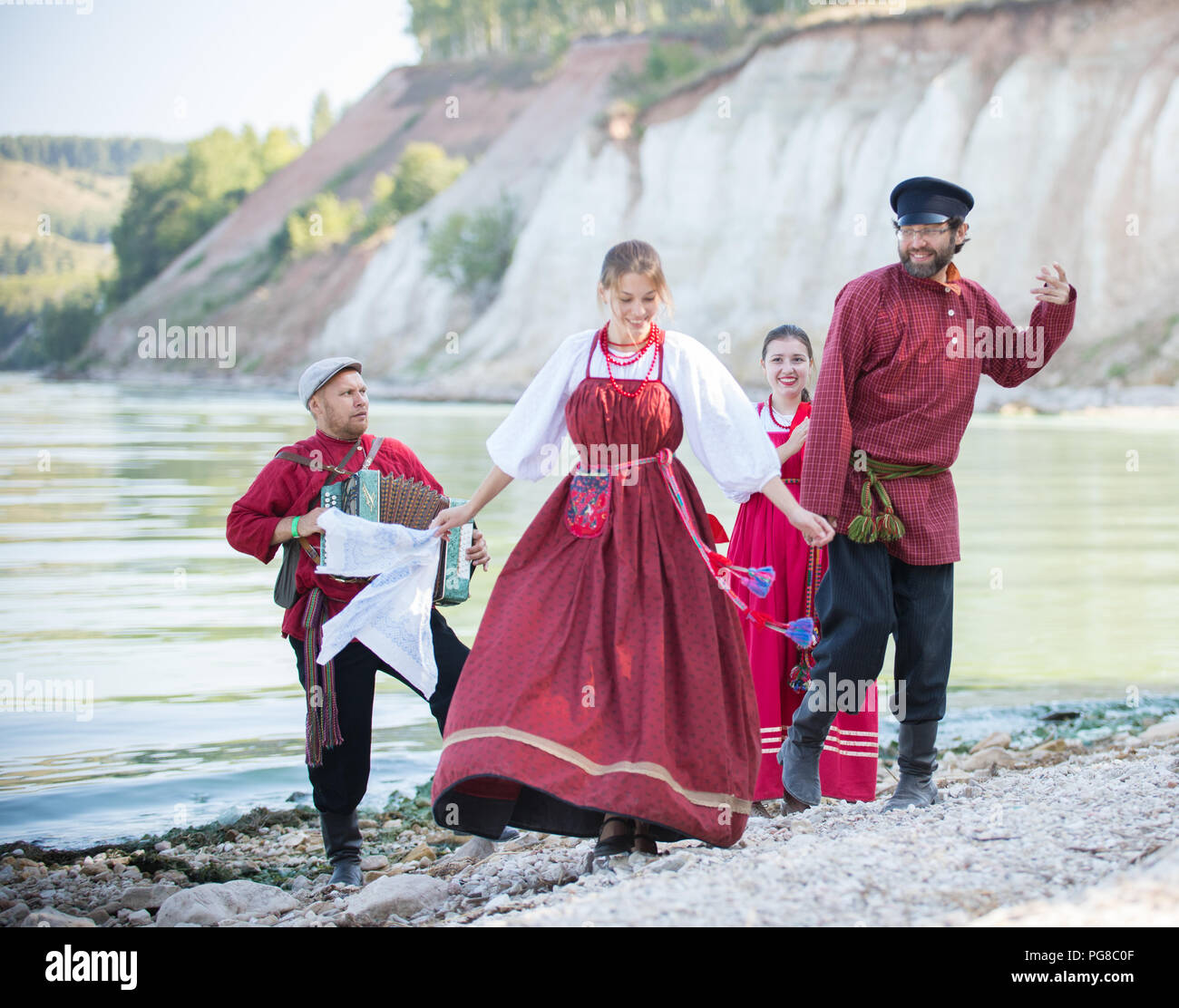 Cheerful people in national Russian costumes dance against the backdrop ...
