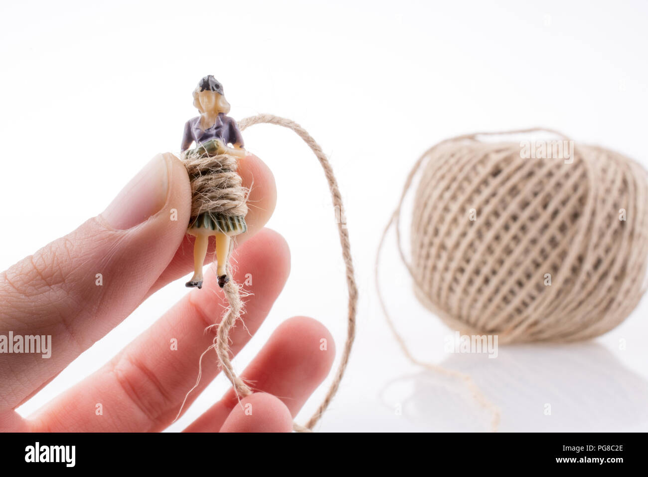 Woman figure in hand beside a linen spool of thread on a white ...