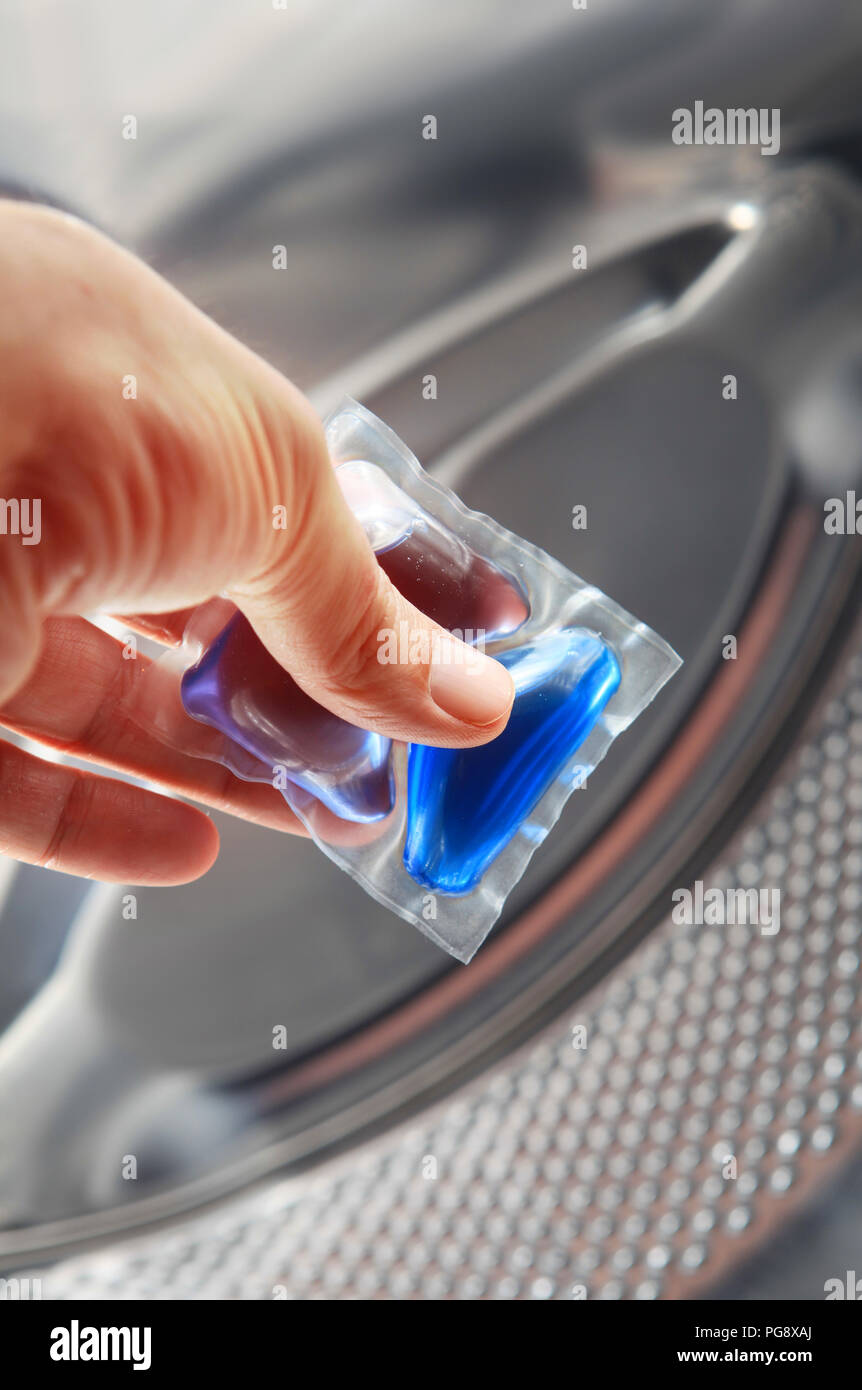 blue gel cap in hand for washing mashine, liquid coloured detergent ...