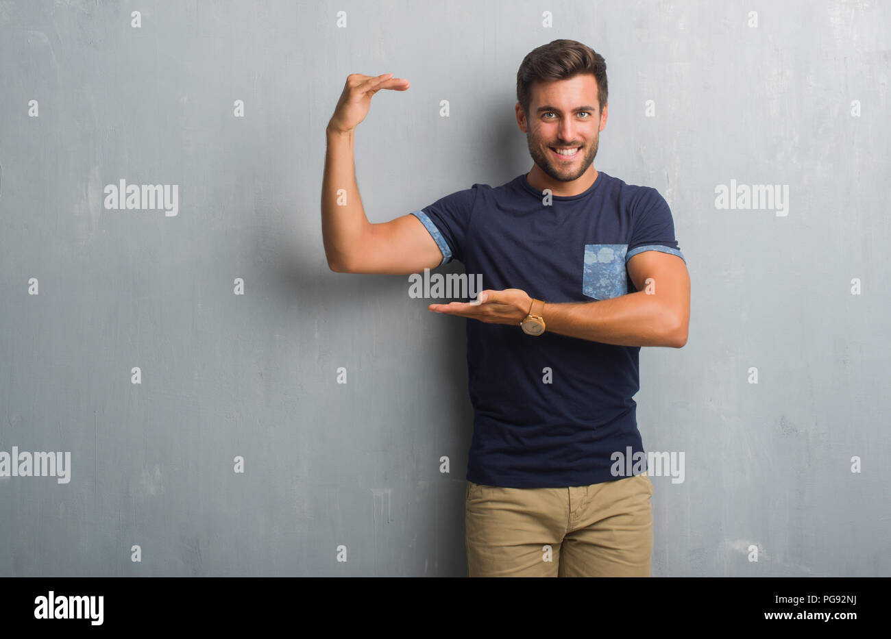 Handsome young man over grey grunge wall gesturing with hands showing ...
