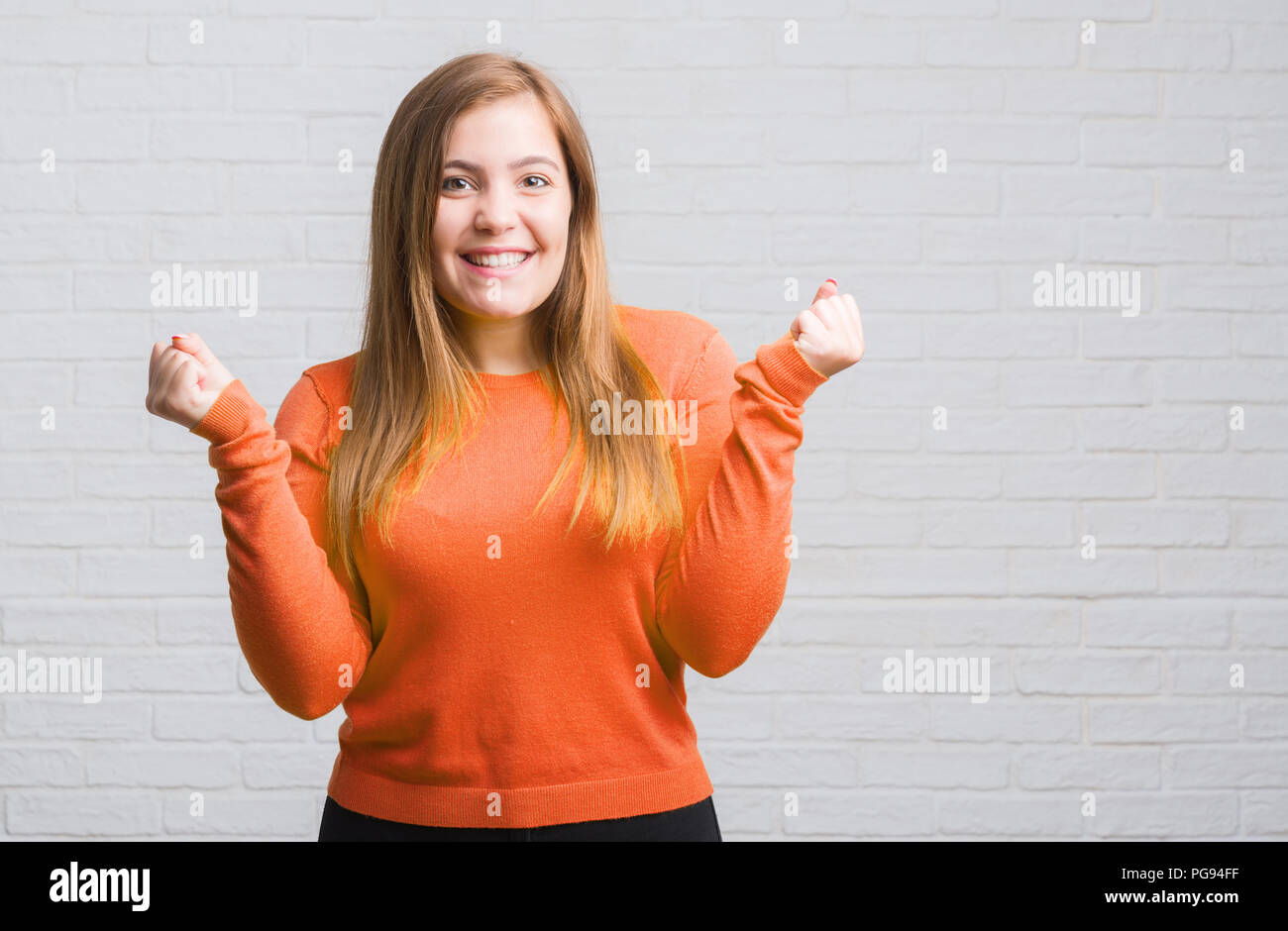 Young adult woman over white brick wall screaming proud and celebrating ...