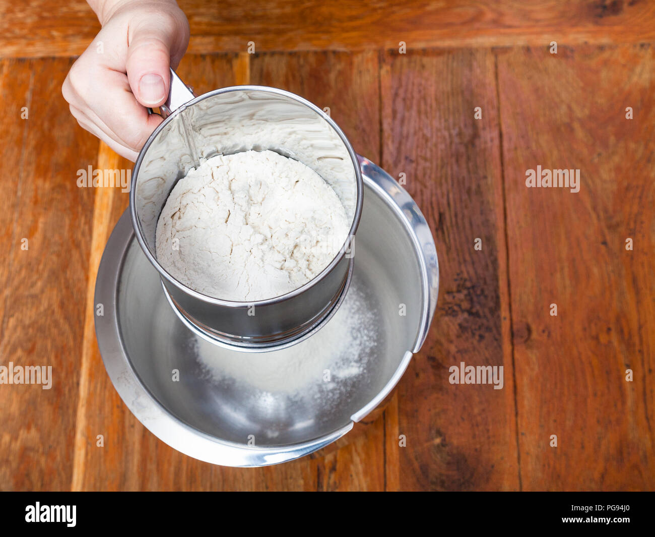 cooking of pie - sifting the flour through sifter into steel bowl Stock ...