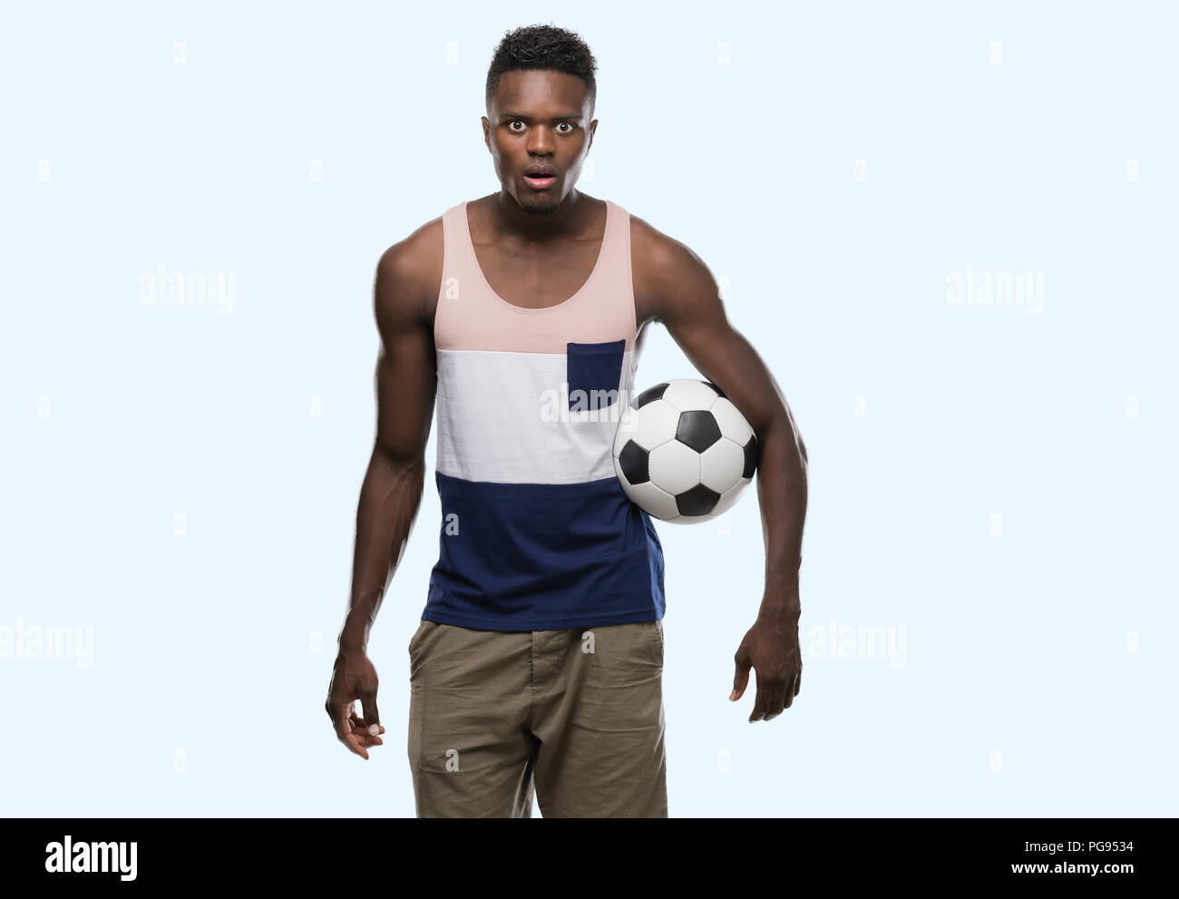 Young african american man holding soccer football ball scared in shock ...