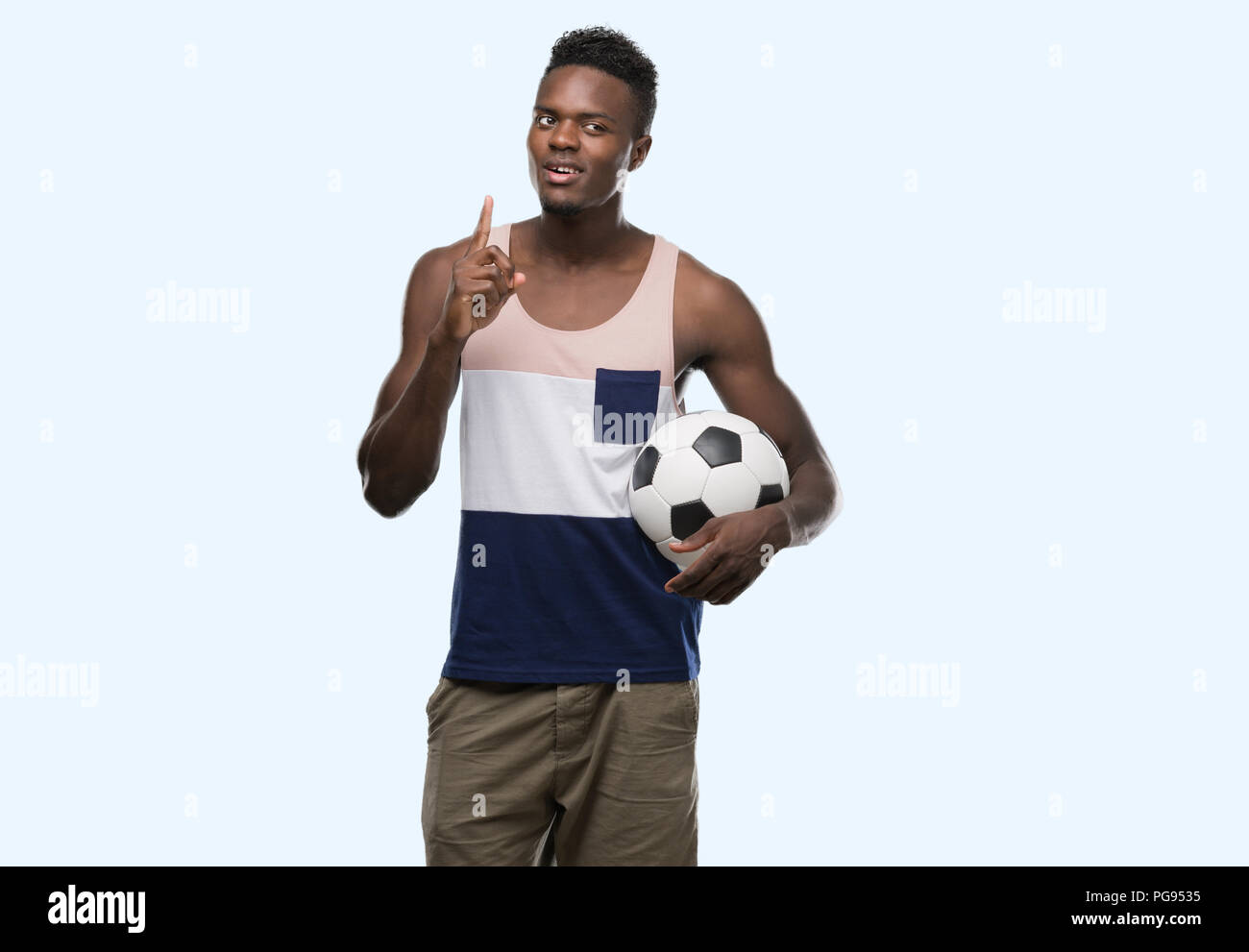 Young african american man holding soccer football ball surprised with ...